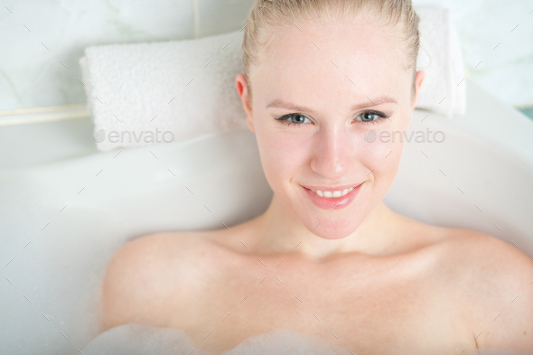 caucasian woman enjoying bathtub. Naturally beautiful female relaxing in bath with foam in ...